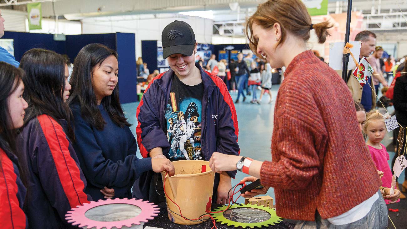 A group of teenagers engaging in a science activity at a science fair.